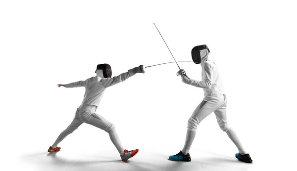 The two men wearing fencing suit practicing with sword against gray ...