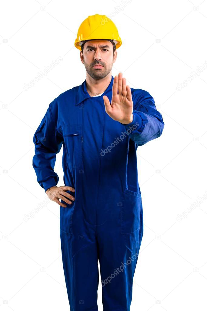 Joven obrero con casco haciendo un gesto de stop con su mano negando ...