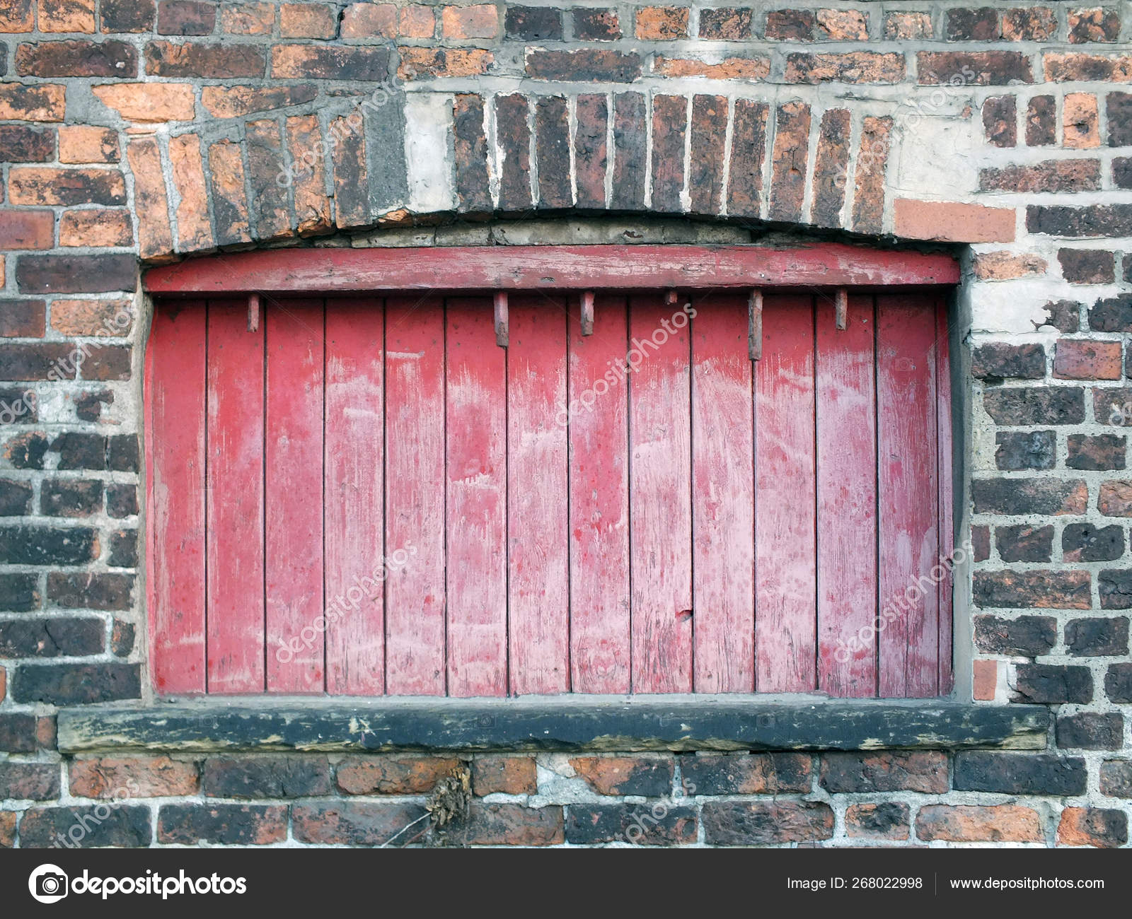 Boarded up window in an old victorian building with faded wood a ...