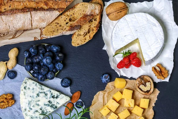 Tasting cheese dish with berries and fruits on old black shale table ...
