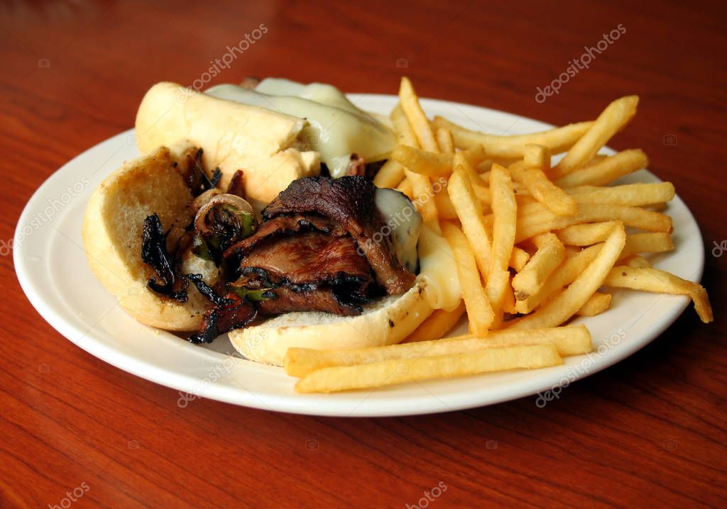 filete de queso con papas fritas en plato blanco y fondo de madera 2023