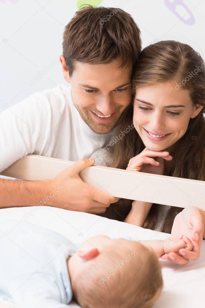 Padres felices cuidando a su hijo bebé durmiendo en la cuna en casa en ...