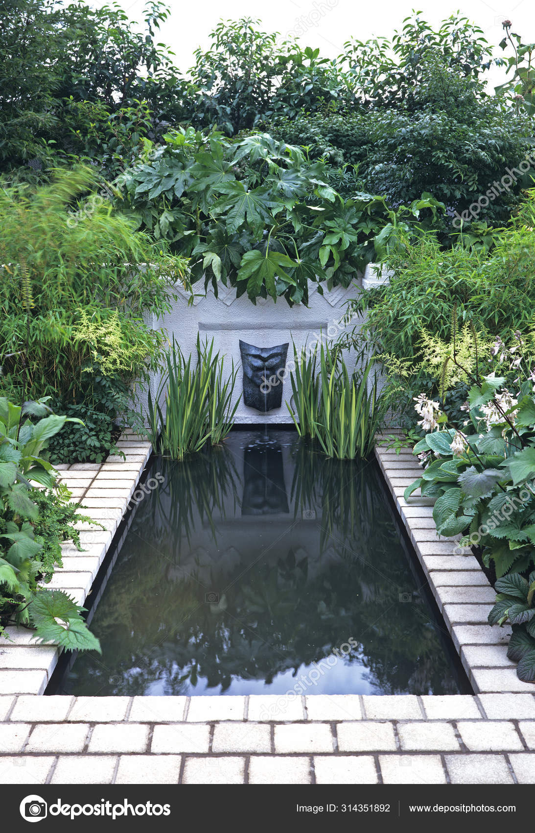 An attractive designed water feature with plants, shrubs and flowers ...