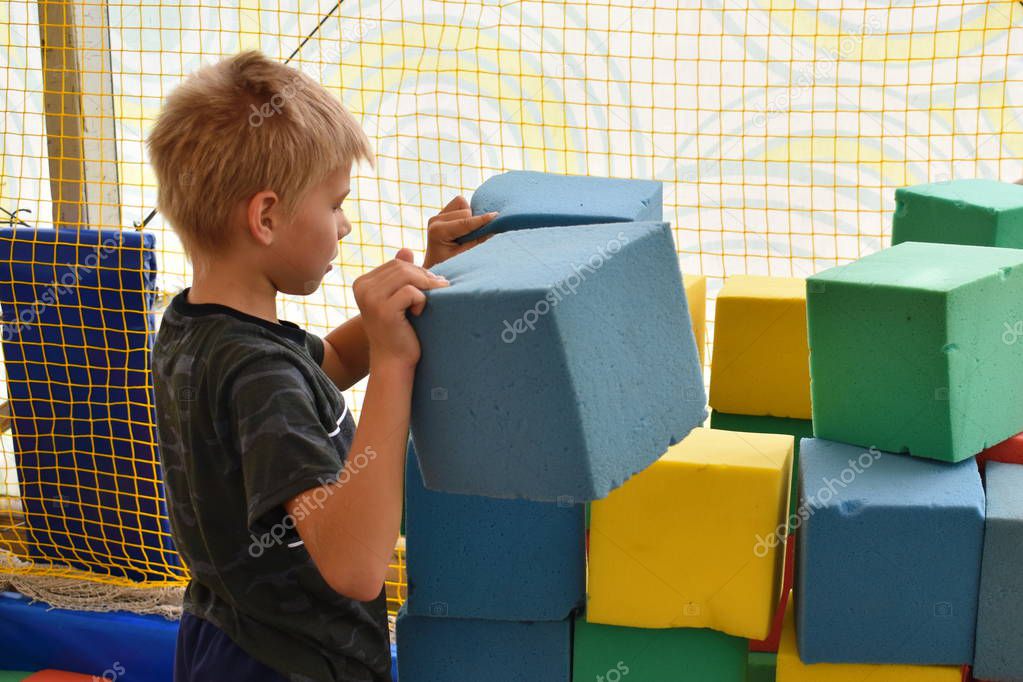 Un niño juega en un patio con cubos. Espuma piscina seca. 2025