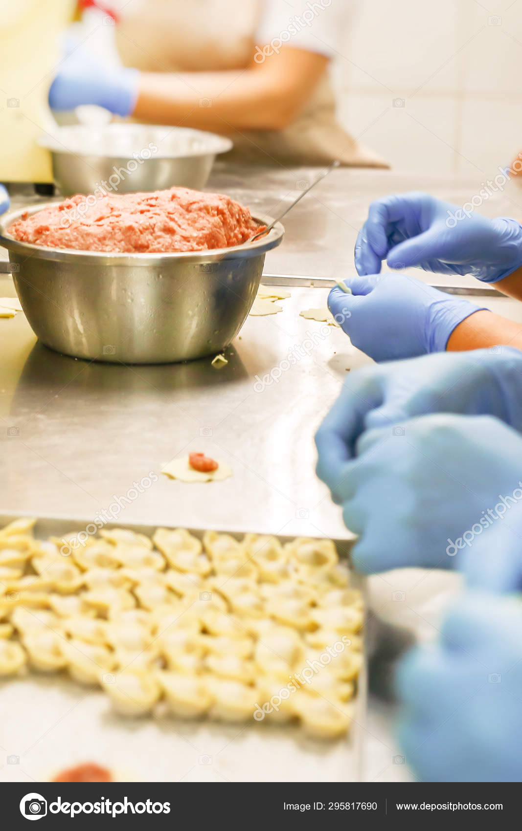 Dumplings manufacturing process. Hands of employers in blue rubber ...
