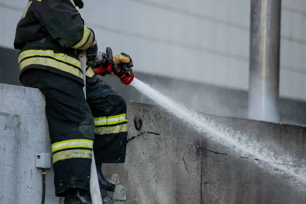 Firemen using extinguisher and water from hose for fire fighting in ...