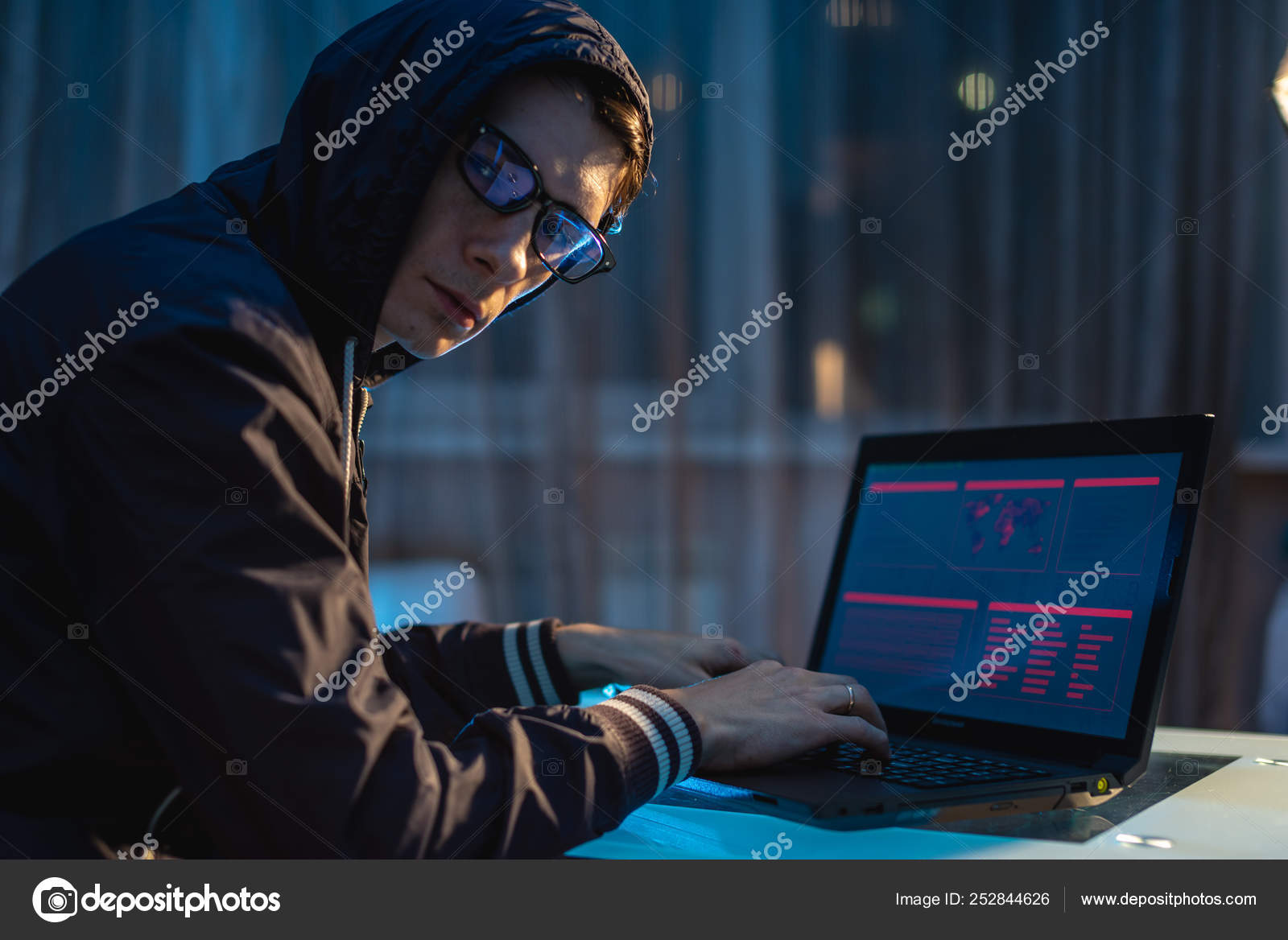Man in the hood looking in the camera. Hacker attacks and stealing access databases with ...
