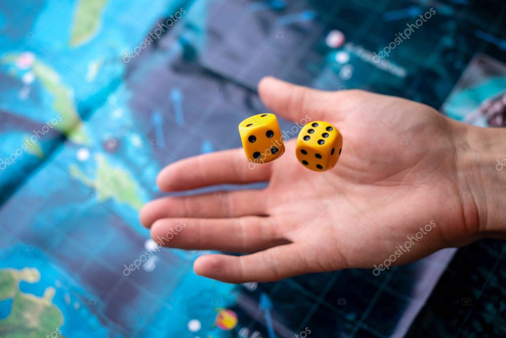 La mano lanza dos dados amarillos en el campo de juego. El concepto de ...