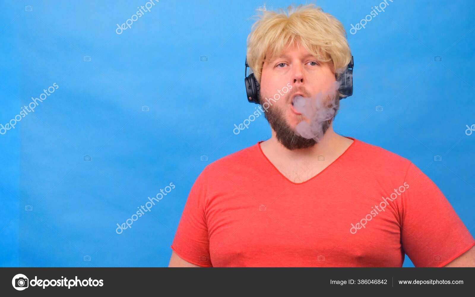Freaky fat man in a wig and a pink T-shirt in his headphones exhales ...