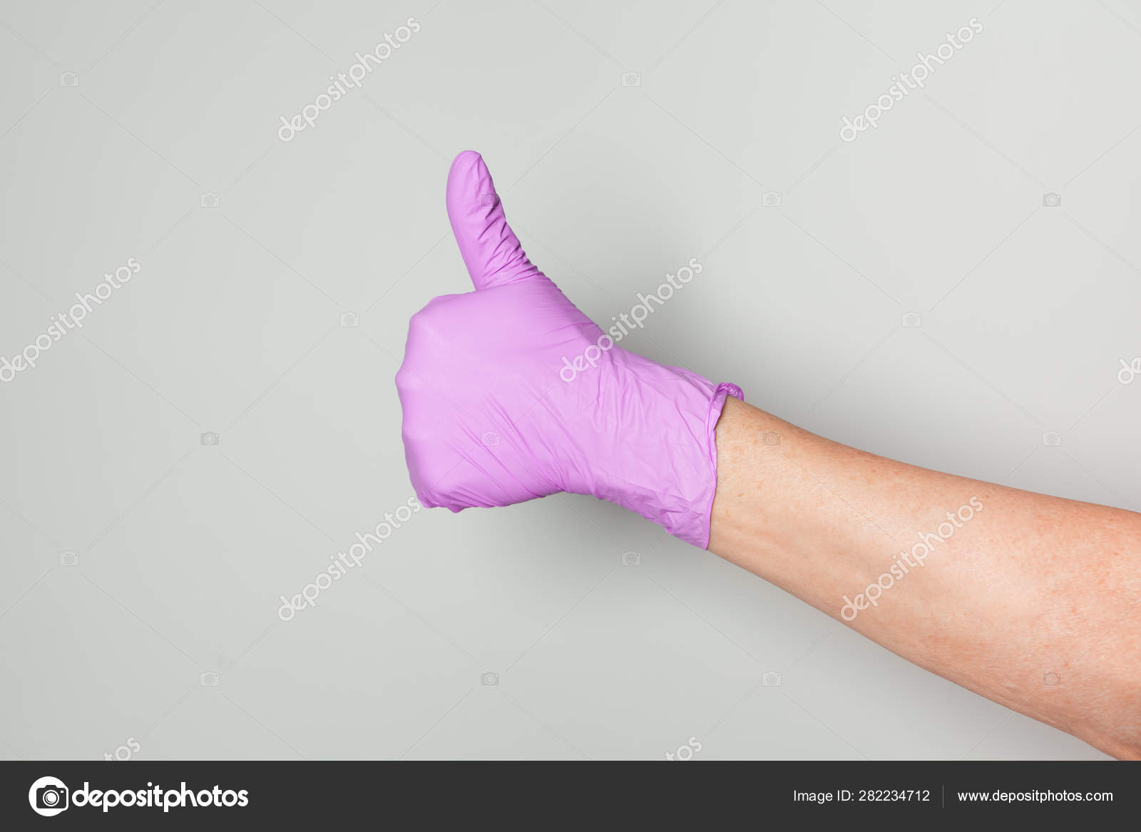 Hand in blue silicone glove on grey background shows the sign OK ...