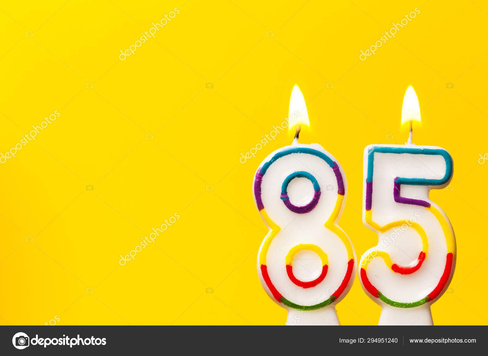 Number 85 birthday celebration candle against a bright yellow ba ...