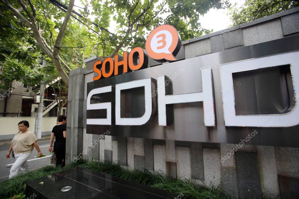 Los peatones pasan por un letrero de SOHO en un edificio de oficinas de SOHO China en Shanghai ...