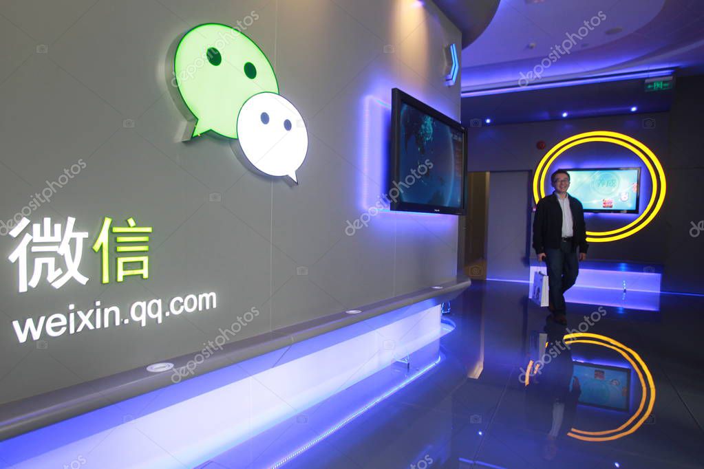 Un empleado chino pasa por delante de un logotipo de Weixin.com (Wechat ...