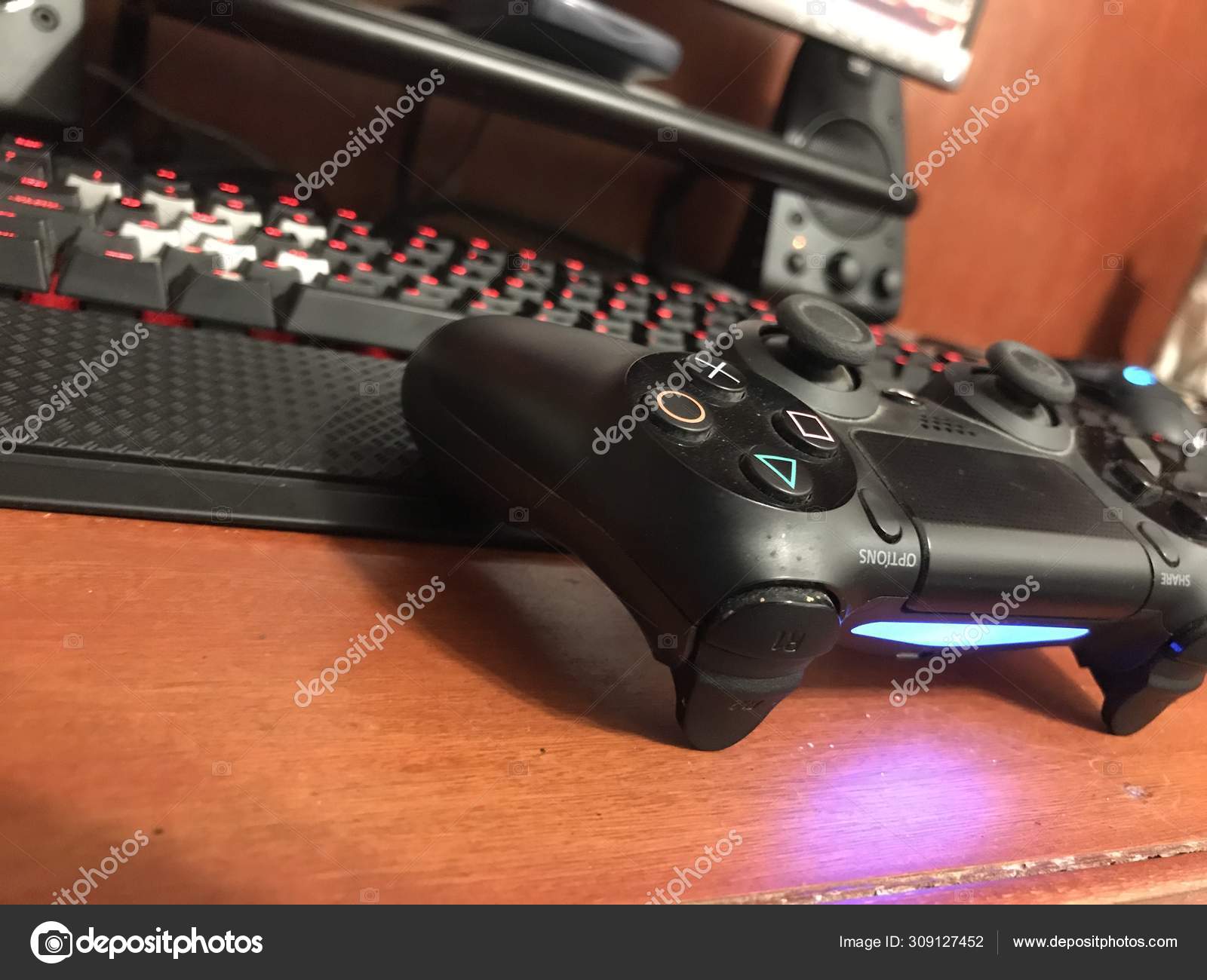 Modern black gaming controller over a wooden desk with a mechanical ...