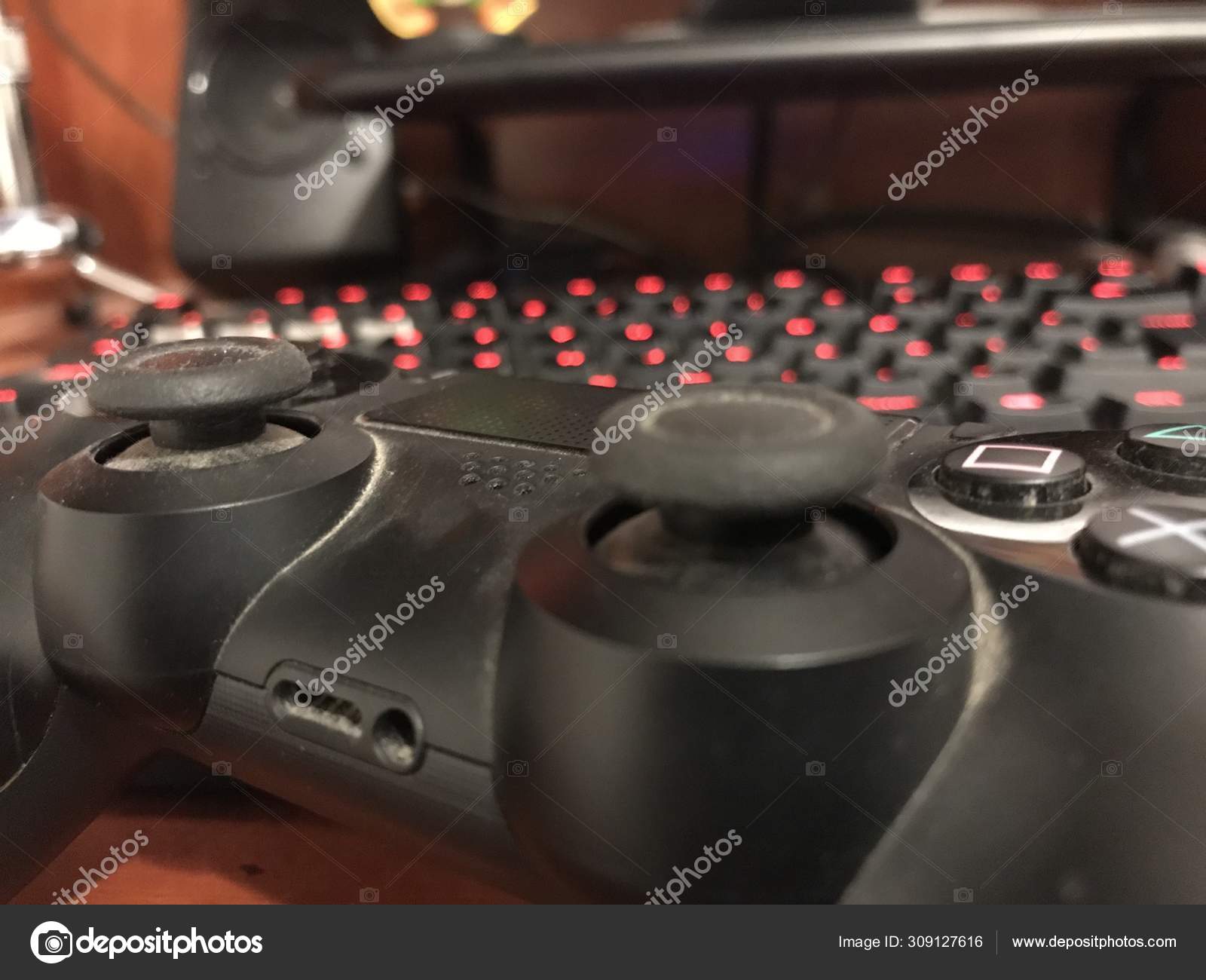 Modern black gaming controller over a wooden desk with a mechanical ...