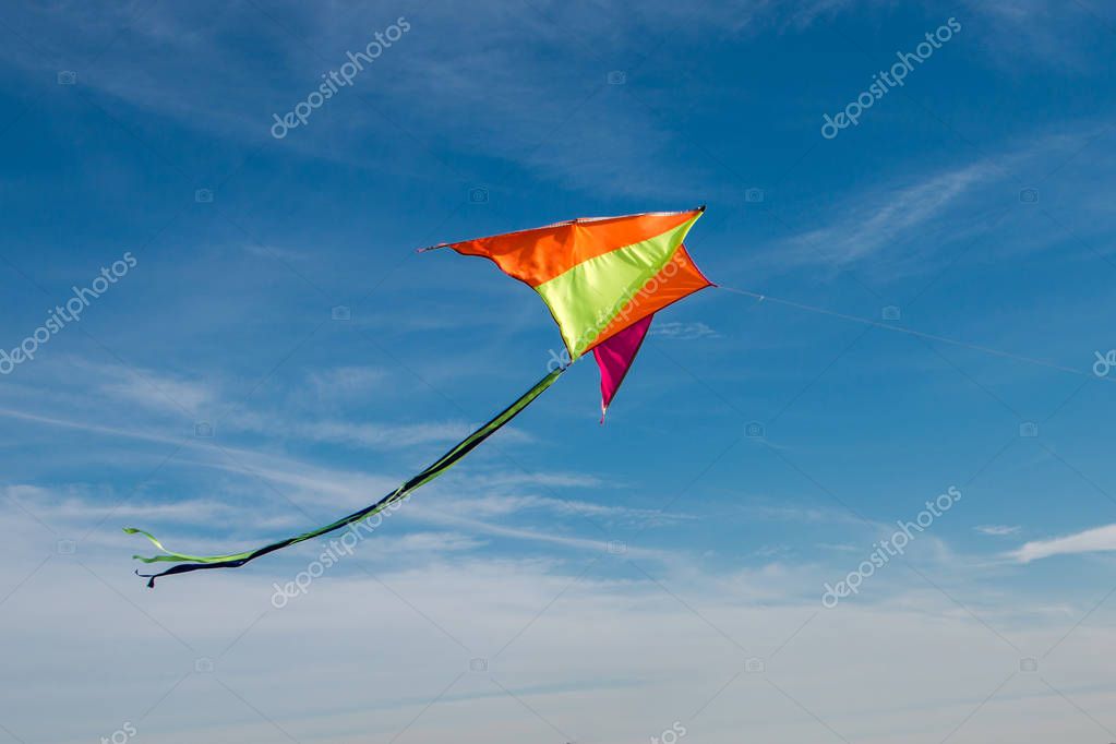 Volando una cometa. Cometa brillante contra el cielo azul. Día soleado ...