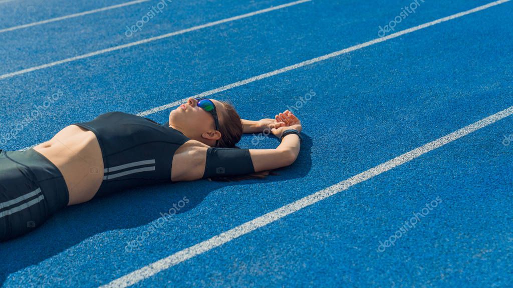 Mujer atleta acostada en la pista de atletismo relajándose después del ...