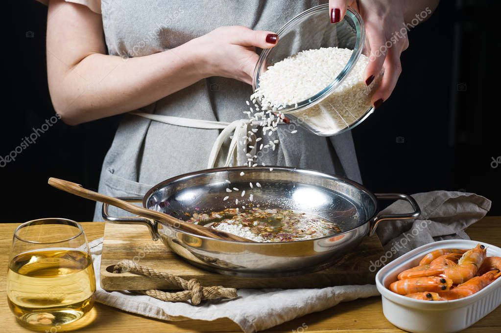 El chef pone el arroz en la sartén para el risotto italiano. Camarones ...