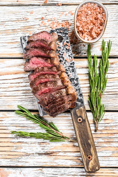 Grilled ramp cap steak on a meat cleaver. White wooden background. Top ...