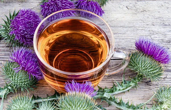 Tea with a thistle and flowers of a thistle medicinal plant on a wooden ...