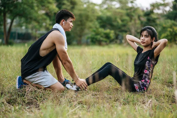 Men pushing women legs to exercise by pushing up. Selective focus ...
