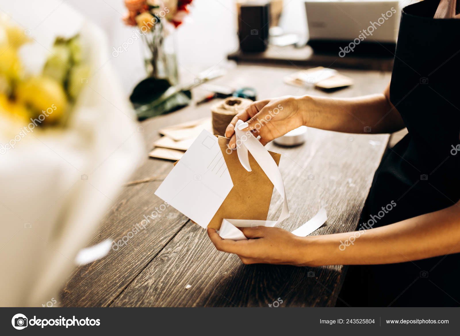 Florist is packing a postcard in an envelope with white ribbon on the ...