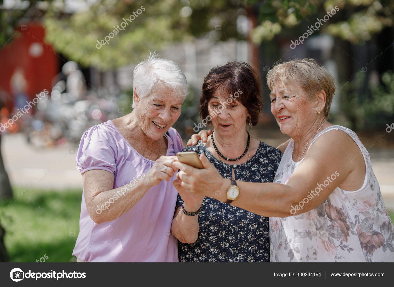 Three old women are smiling and looking photos at the at screen of the ...