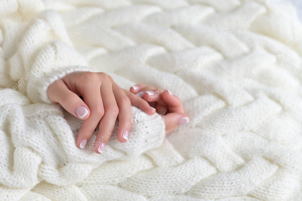 Hermosas manos de mujer con manicura francesa en el fondo de un suéter ...
