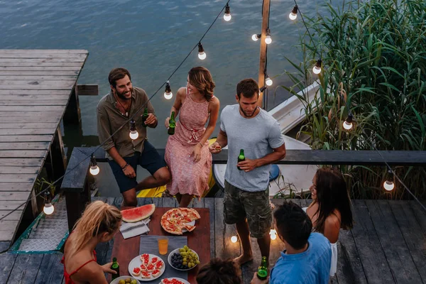 Group of young people having outdoor dinner party by the river. - Stock ...