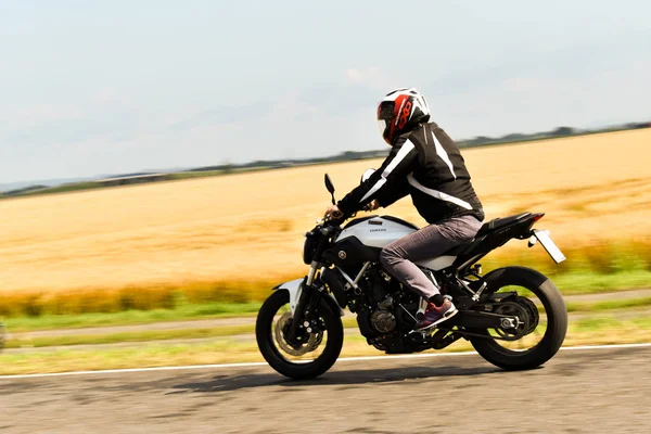 Young man riding motorcycle in asphalt road curve with with a mo ...