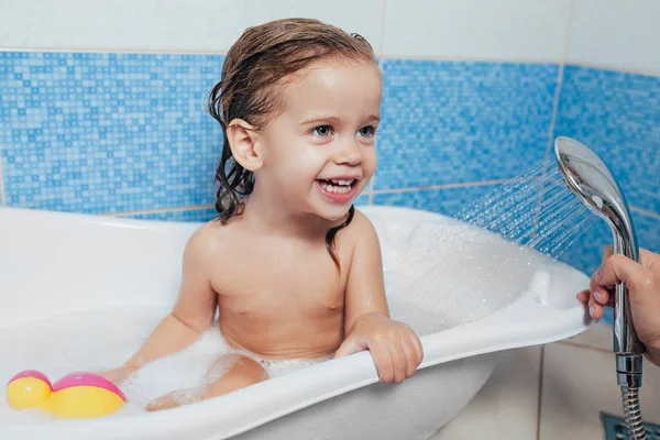 Beautiful little girl taking a bath. A child is played with water and ...