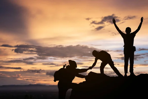 Friends helping each other trying to reach top of mountains during ...