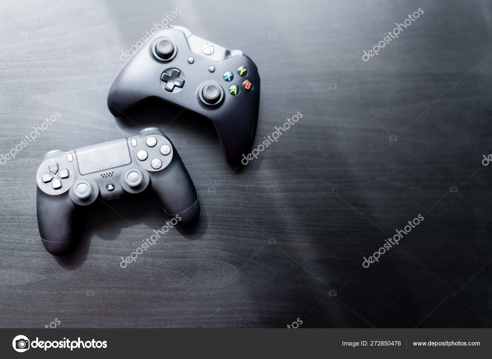 Xbox and Playstation controller sat next to each other on a dark ...