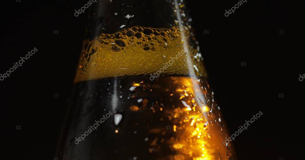 Botella de cerveza fría sobre fondo negro. Condensado 2023