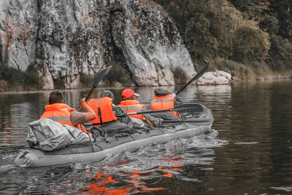 A group of friends in an inflatable raft moving down a river - Stock ...