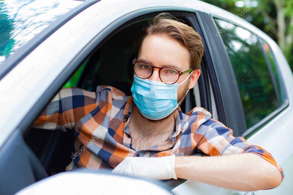 Hombre con guantes protectores y mascarilla, conduciendo un coche ...