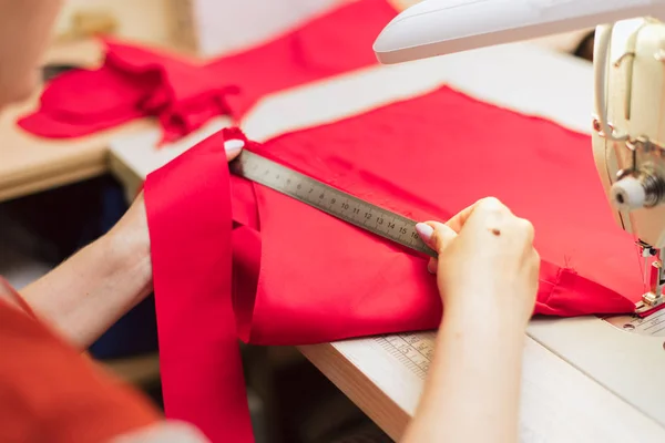 Tailor measures fabric with a ruler. Woman works in a garment factory ...