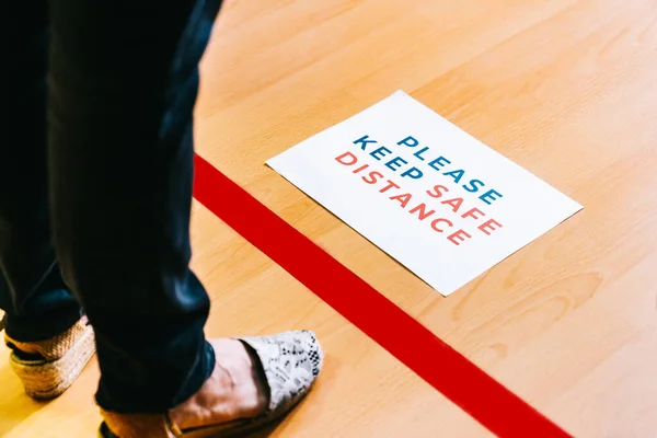 Please keep safe distance. Woman waiting behind a red line to enter a ...