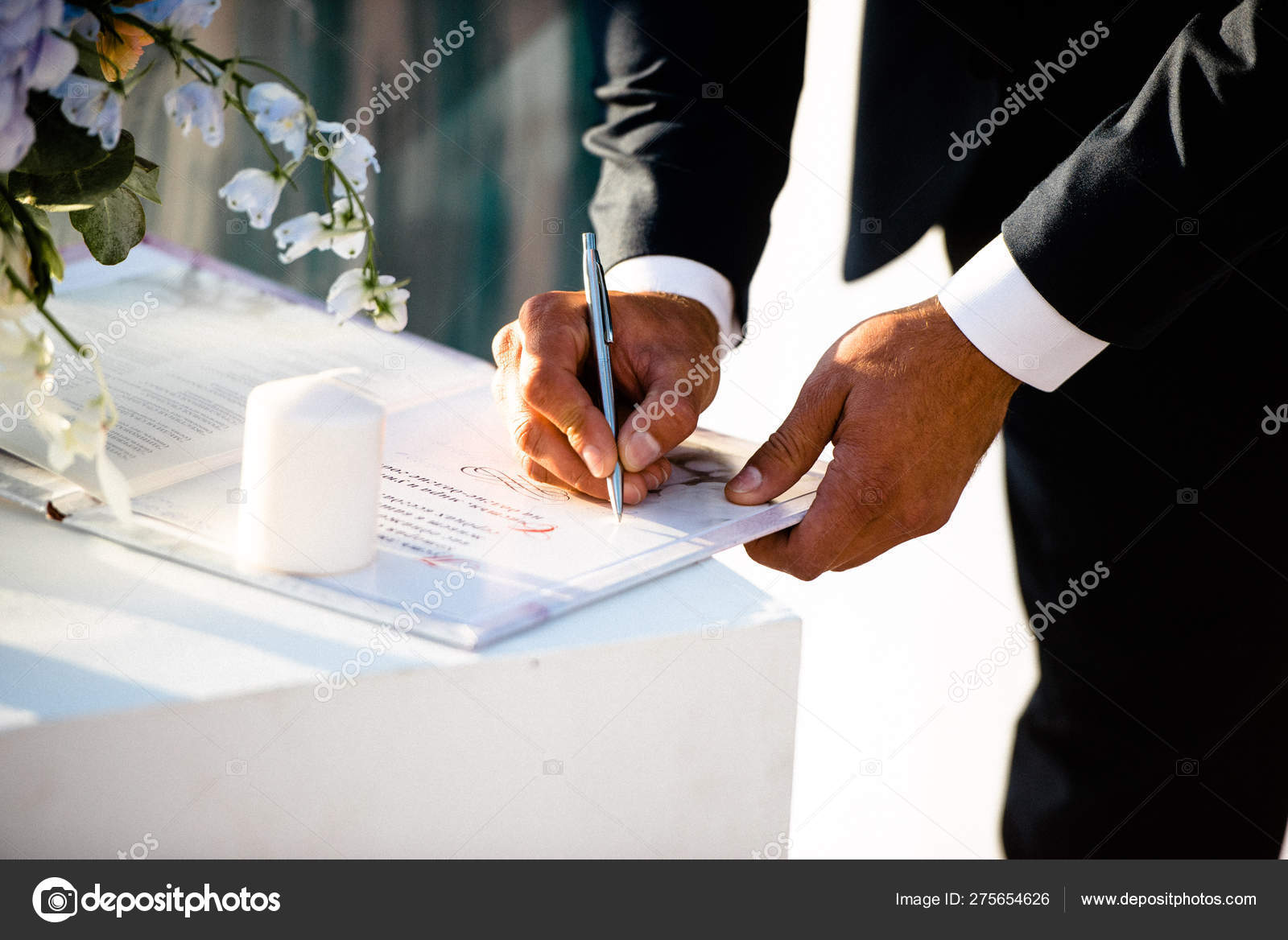 The groom at the wedding ceremony puts his signature on the document ...