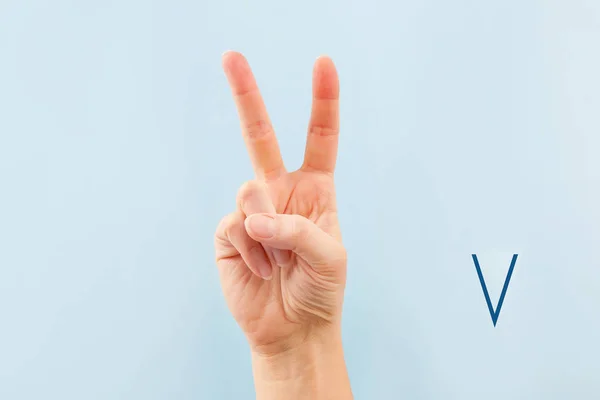 American sign language. Female hand showing letter V isolated on blue ...