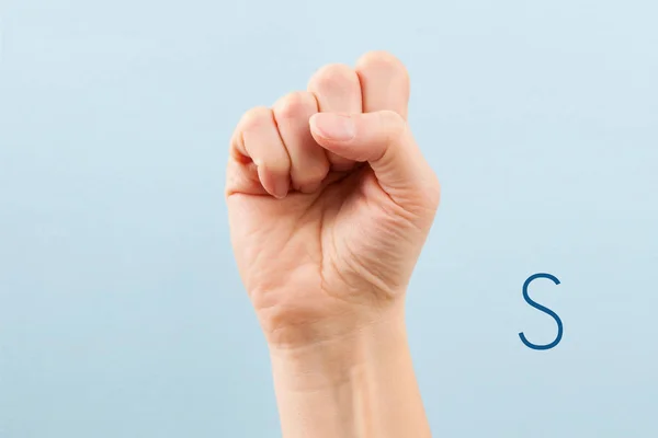 American sign language. Female hand showing letter S isolated on blue ...