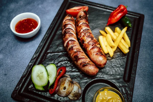 Two meat grilled sausages with vegetables served on the plate ...