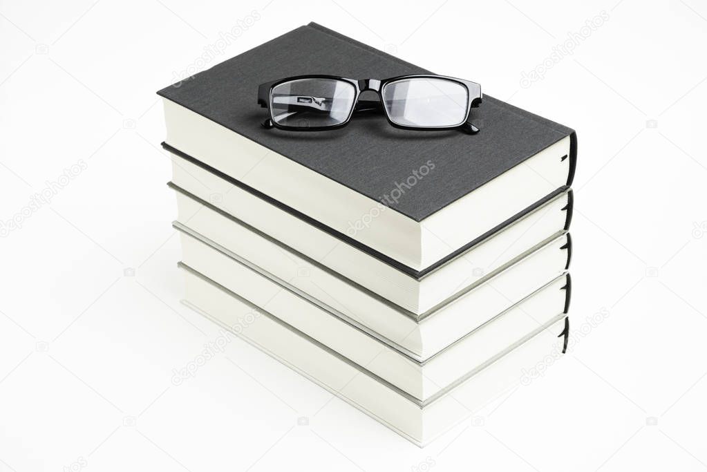 Un conjunto cuidadosamente apilado de cinco libros con gafas de lectura ...