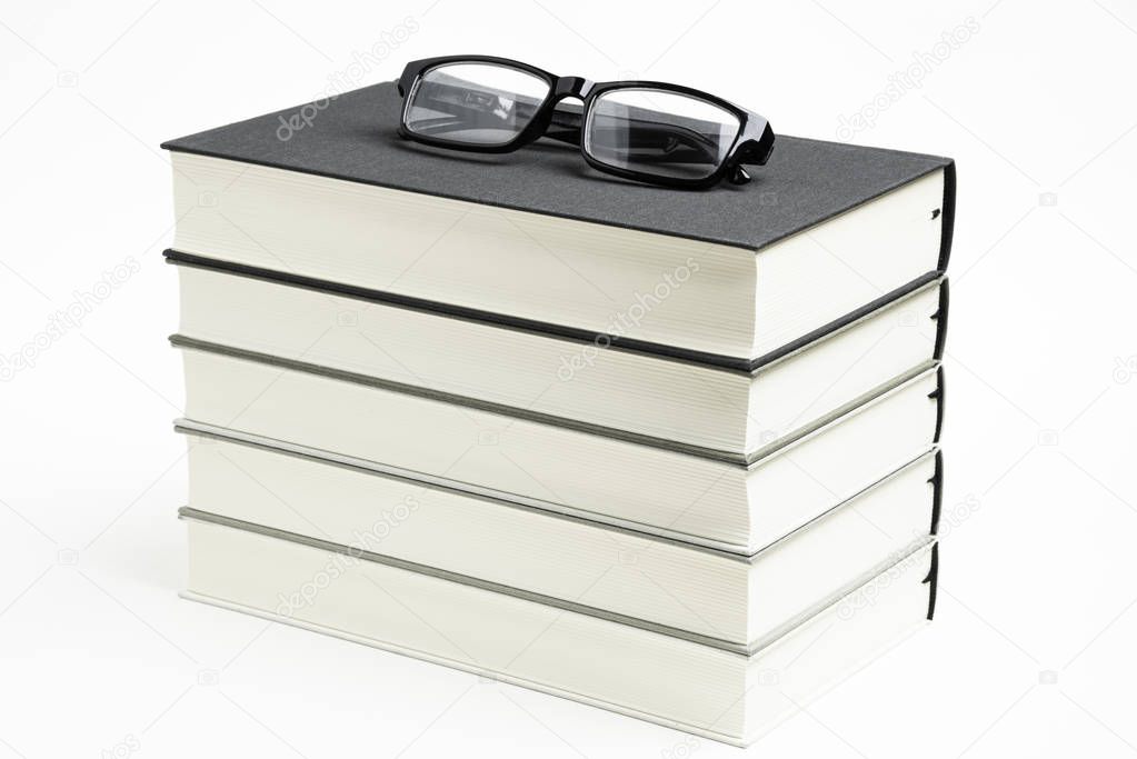 Un conjunto cuidadosamente apilado de cinco libros con gafas de lectura ...