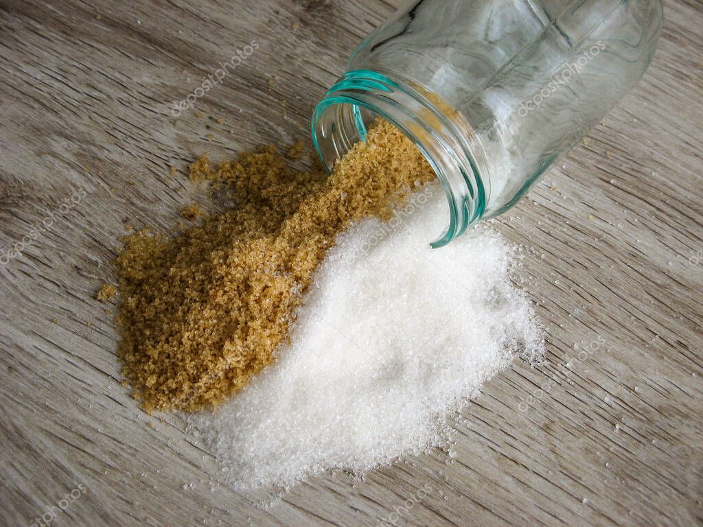Azúcar blanco y moreno en botella de vidrio sobre fondo de madera ...