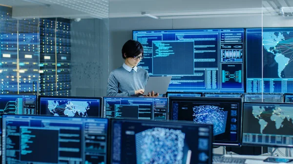 In the System Control Room IT Technician Holds and Works on a Laptop ...