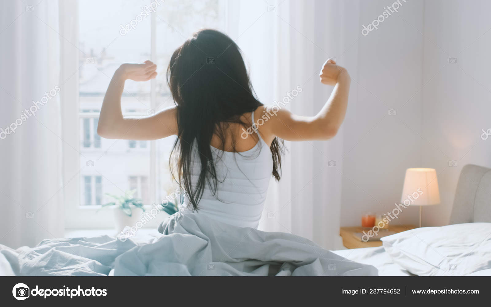 Beautiful Brunette is Waking up in the Morning, Stretches in the Bed ...