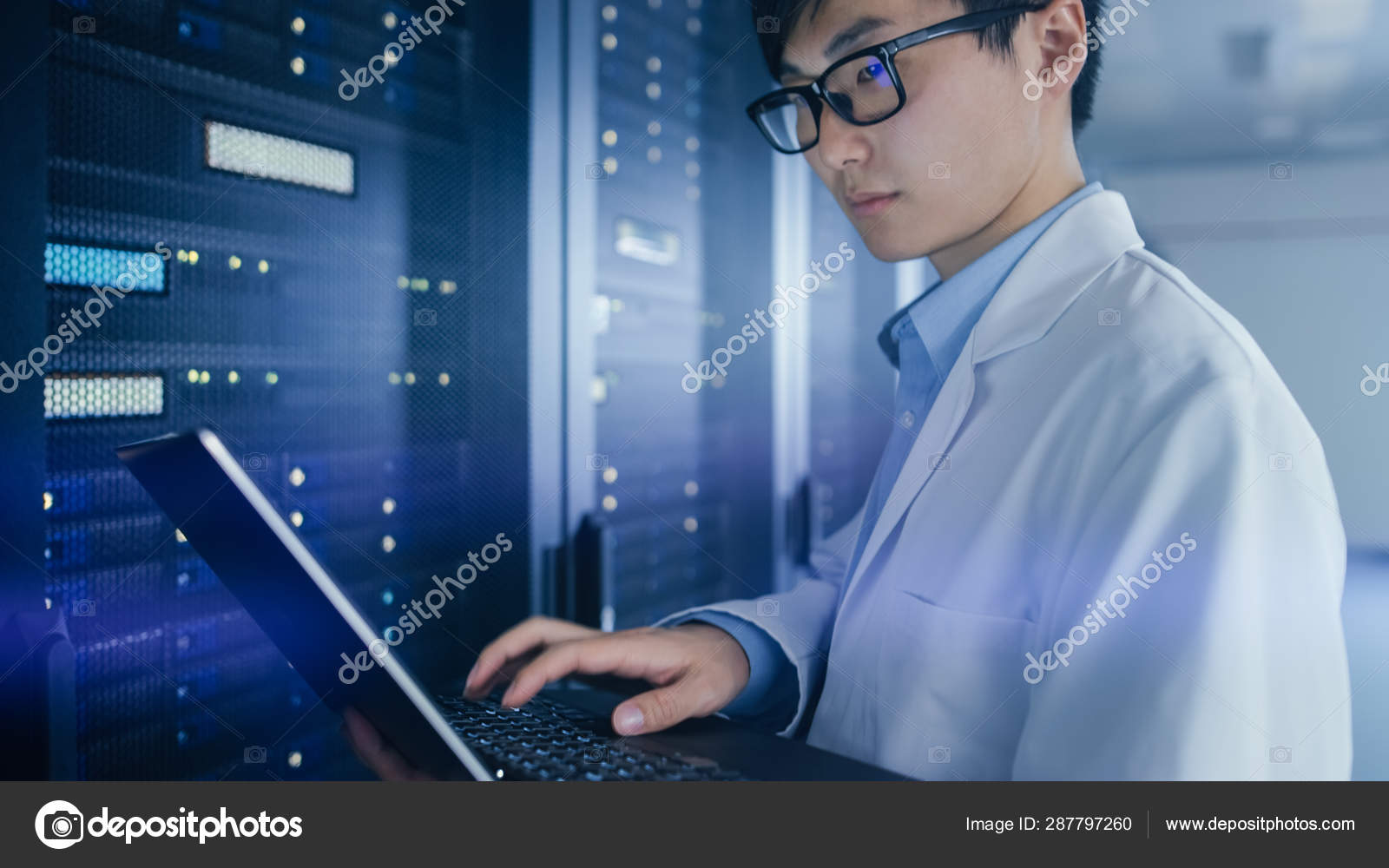 In Data Center: Male IT Specialist Wearing White Coat Stands Beside ...