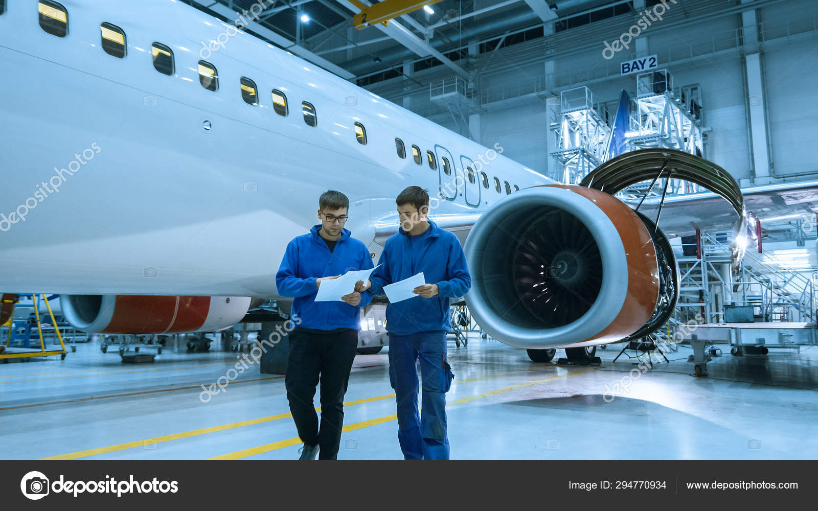 Aircraft maintenance mechanic uses tablet in front of a airplane cabin ...