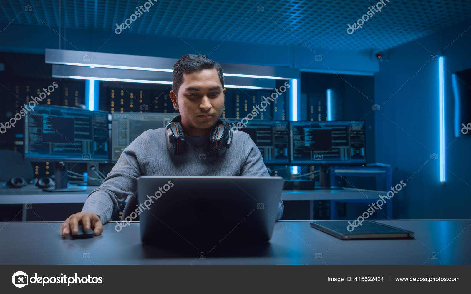 Portrait of Handsome Indian Software Developer Hacker Gamer Wearing Headset Sitting at His Desk ...